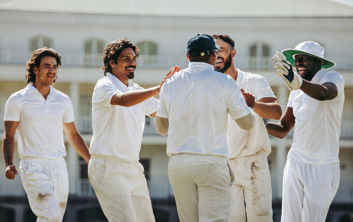 Cricket players celebrating a victory outdoors in a sports team settin ...