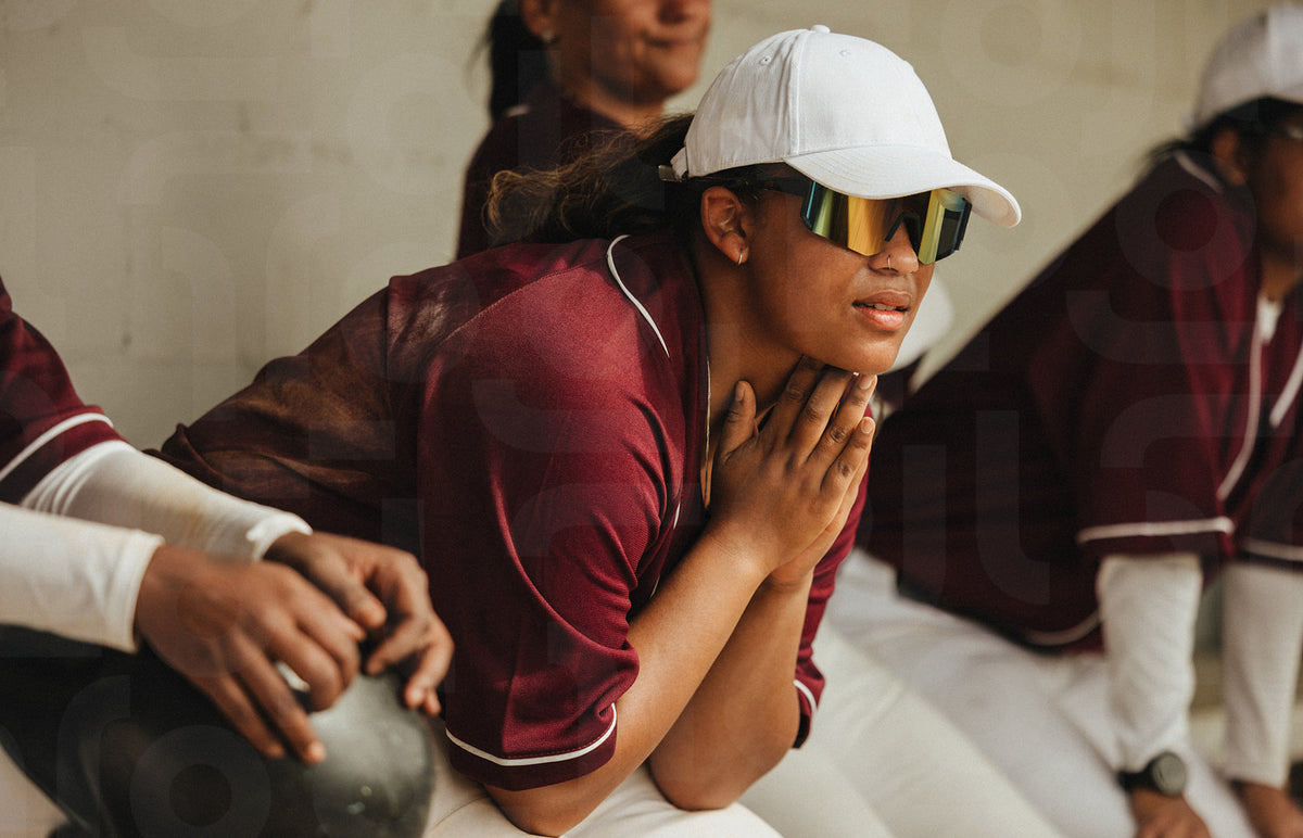Focused female baseball player pondering game strategy and teamwork ...