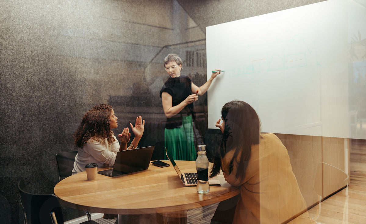 Three women engaged in a collaborative discussion in a small meeting r ...