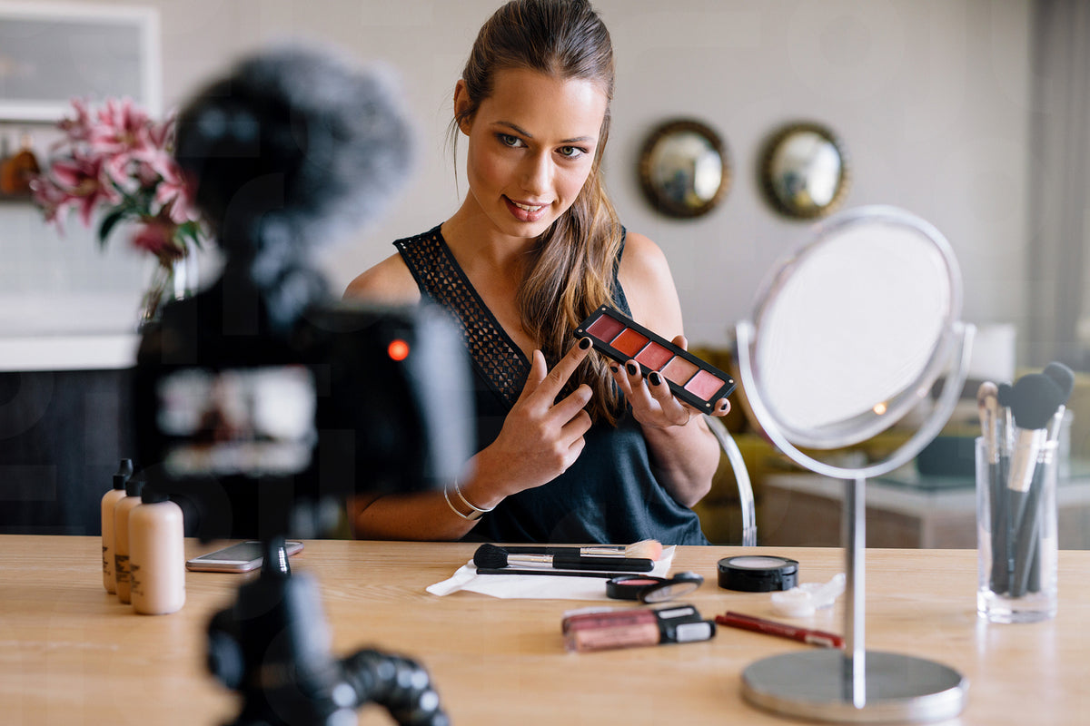 Young female vlogger recording a make-up broadcast for her vlog ...