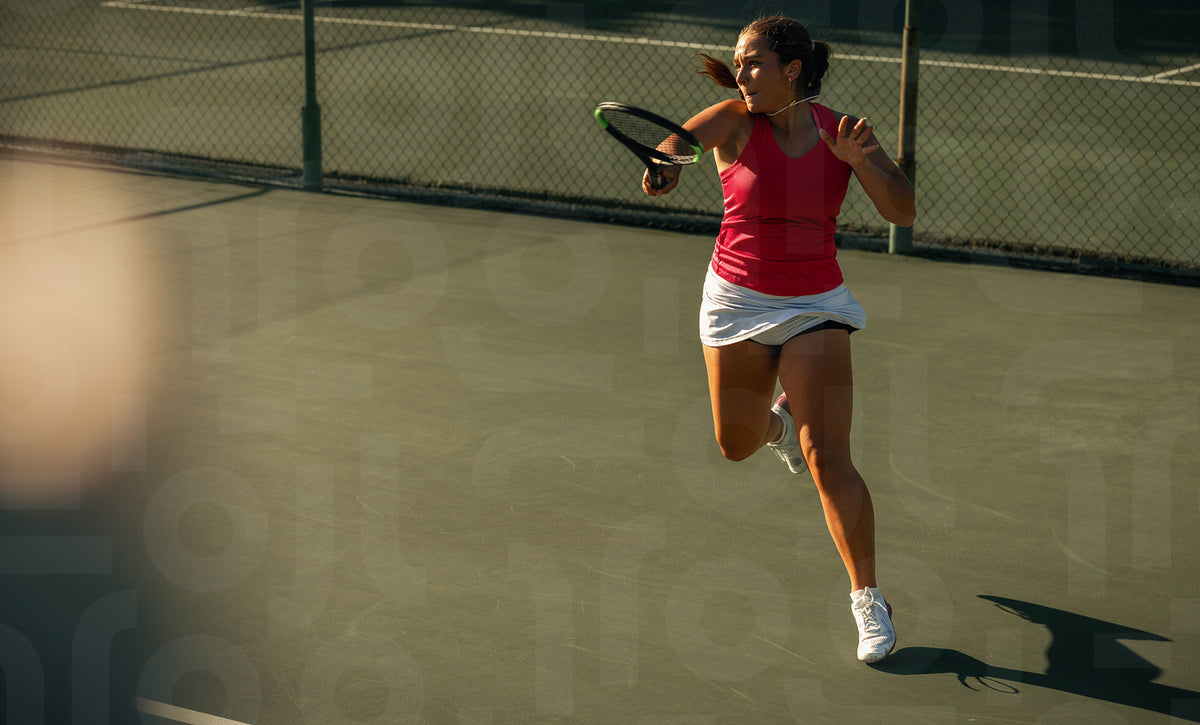 Female tennis player hitting powerful forehand during training session ...
