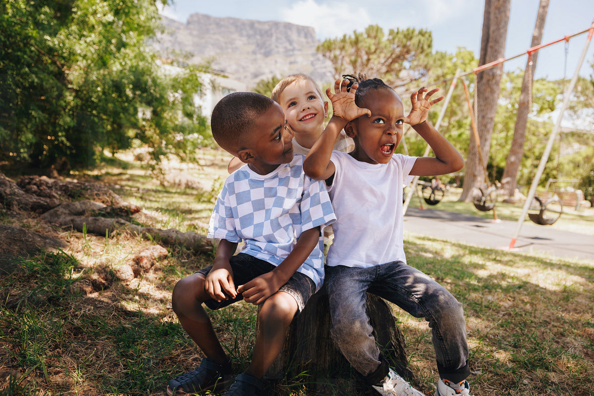 Three children enjoying playtime together outdoors in a sunny park ...