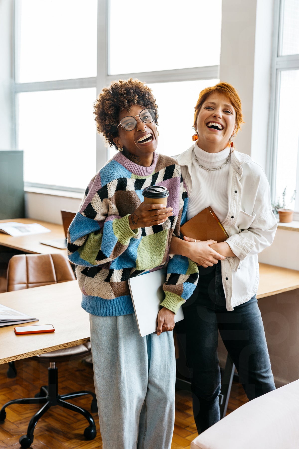 Diverse colleagues laughing together in a modern co-working space ...