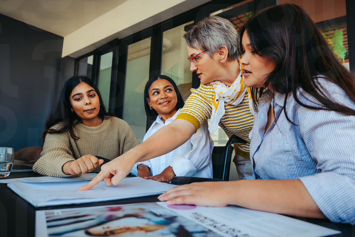 Teacher instructing a diverse group of young women on homework assignm ...