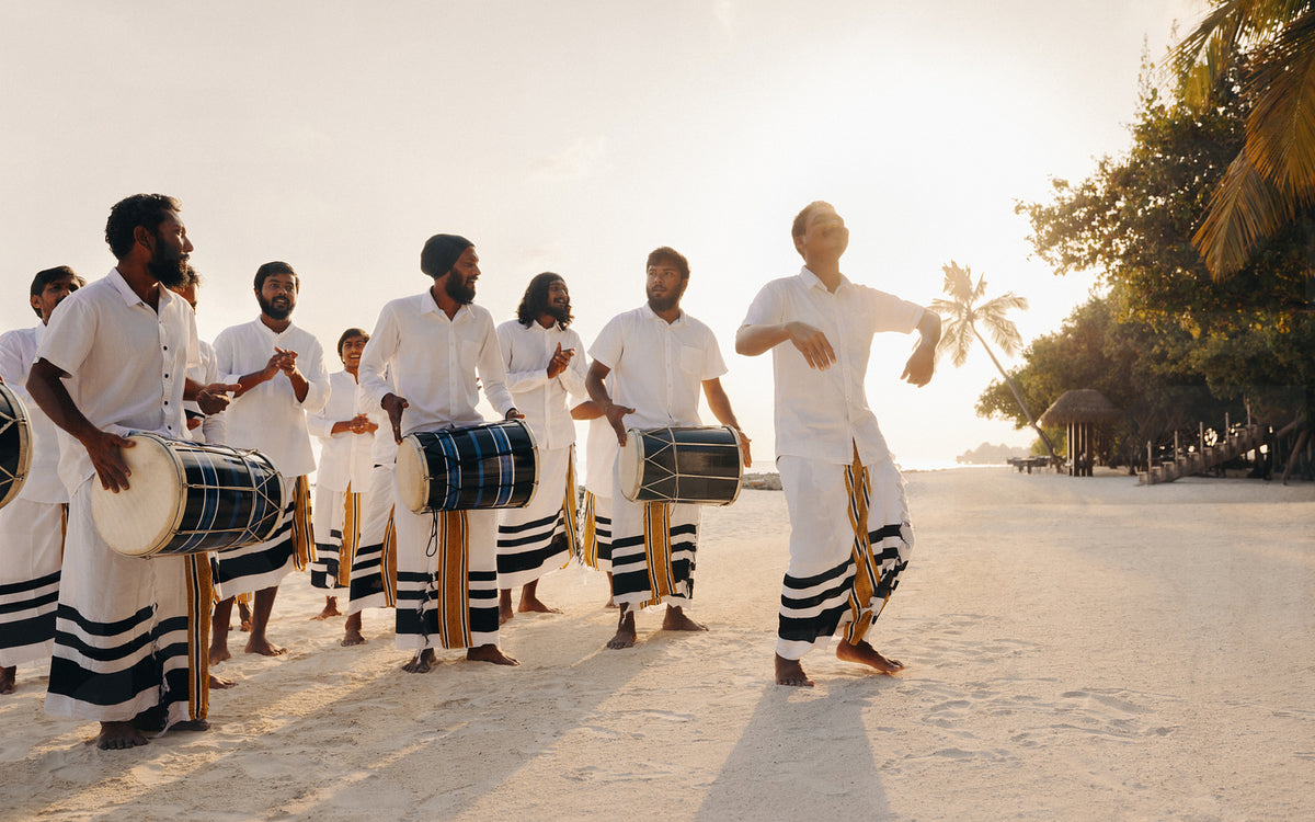 Traditional island entertainment with dancers on sandy resort beach ...