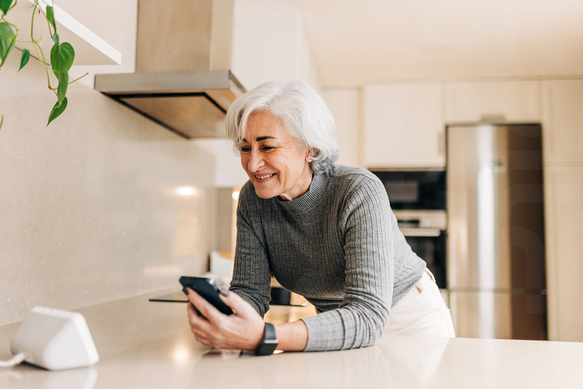 Senior woman talking to a virtual assistant on her smart speaker ...