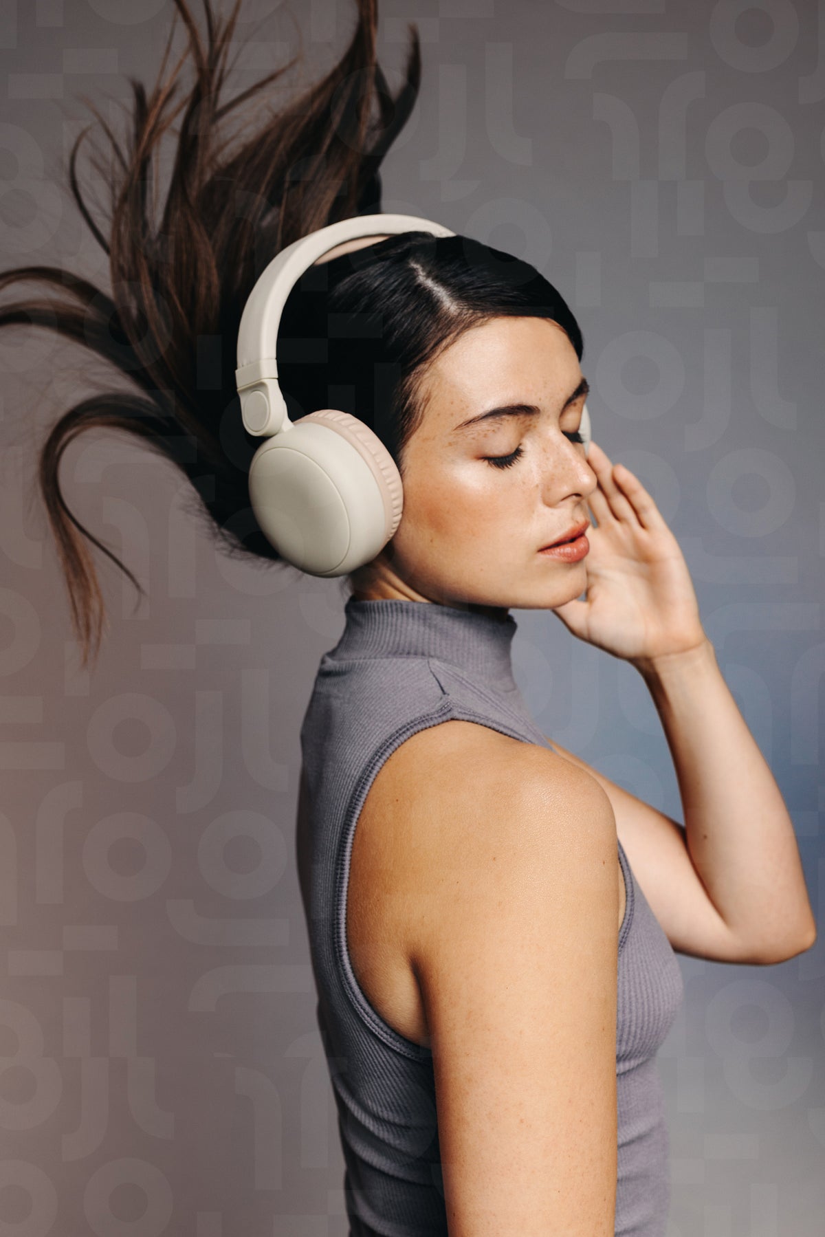 Young woman flipping her hair while listening to music on headphones ...