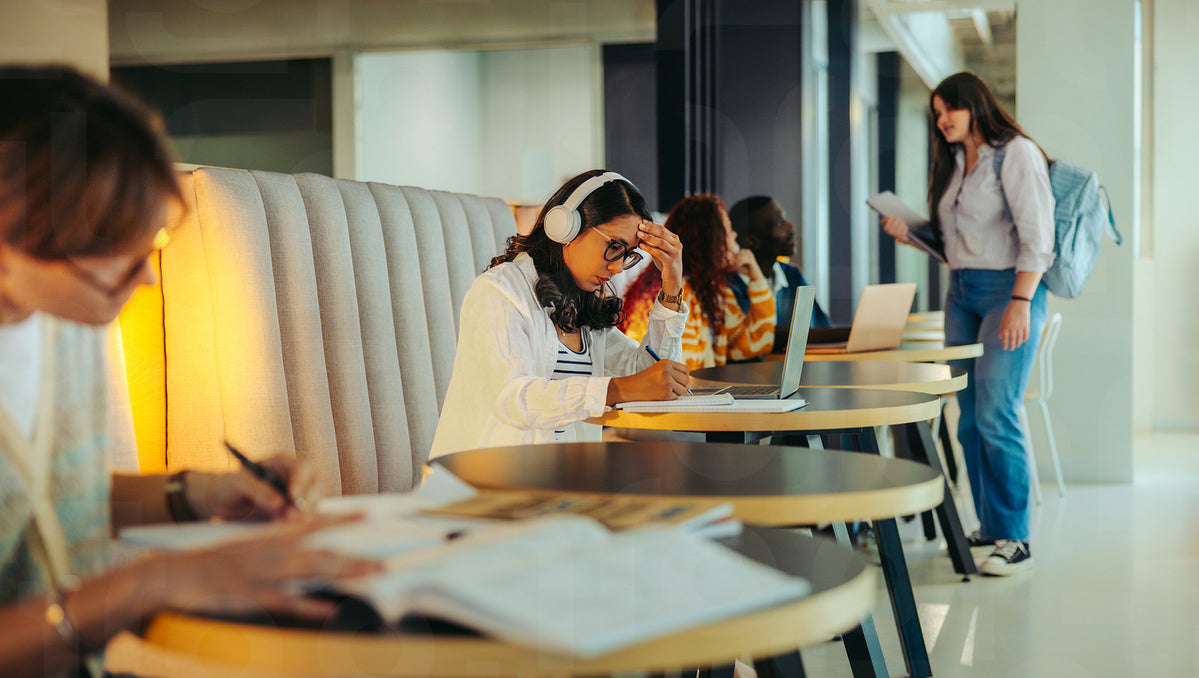 Focused college students studying together in a modern library space ...