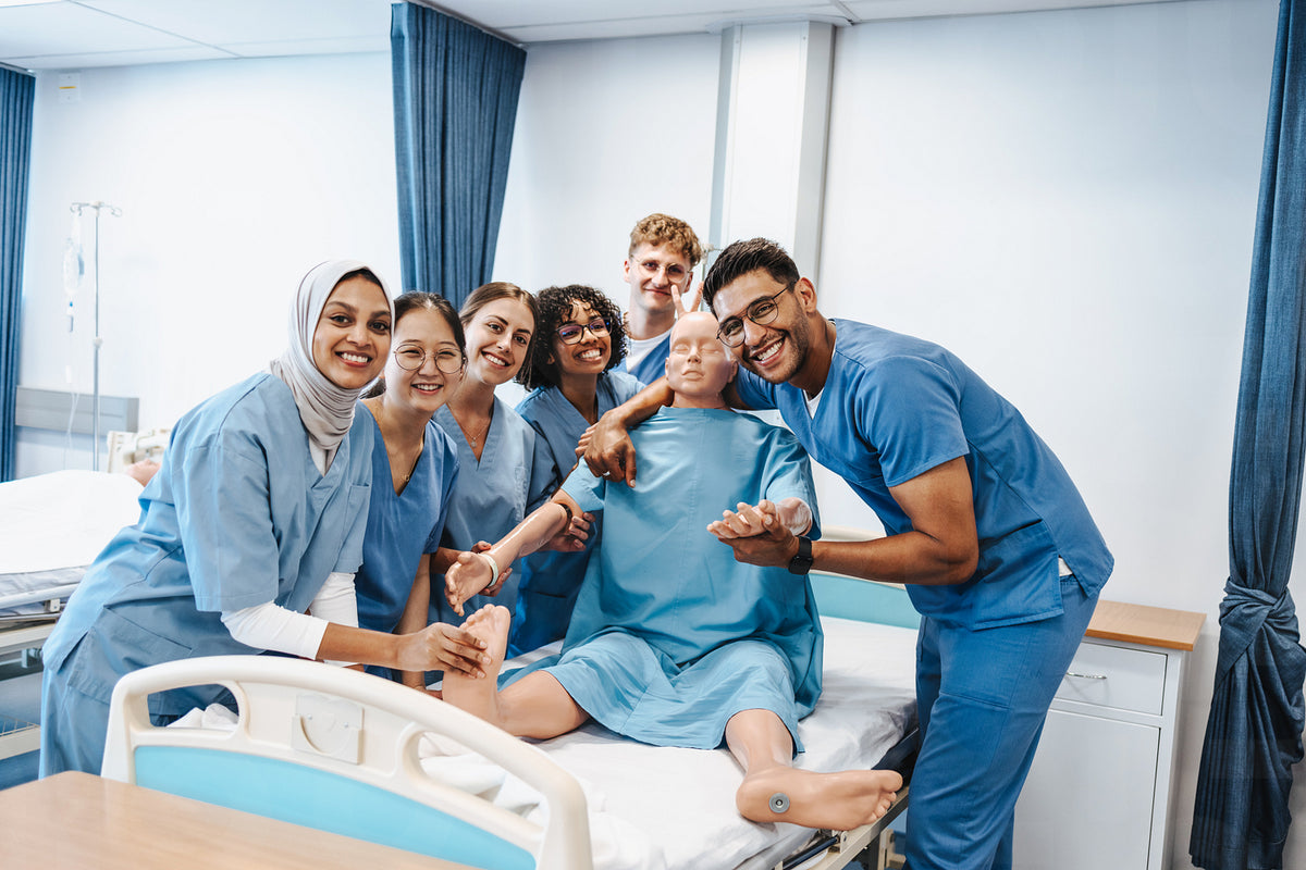 Diverse medical class posing with a patient simulator in a teaching ho ...