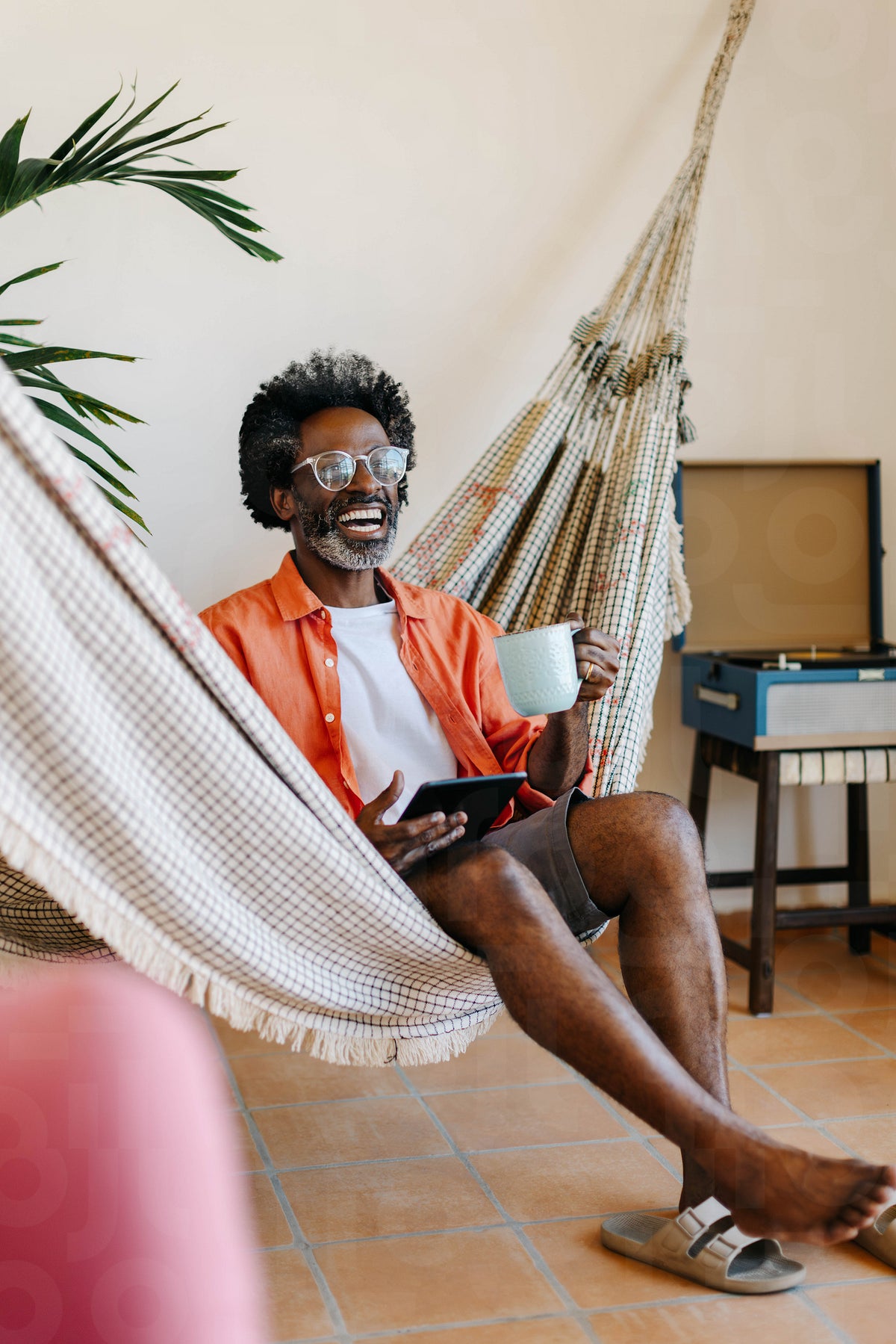 Mature black man relaxing in a hammock with a tablet and hot coffee ...