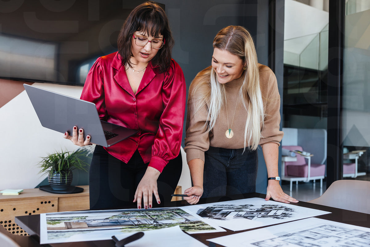 Two women collaborating on architectural designs at a modern workplace ...