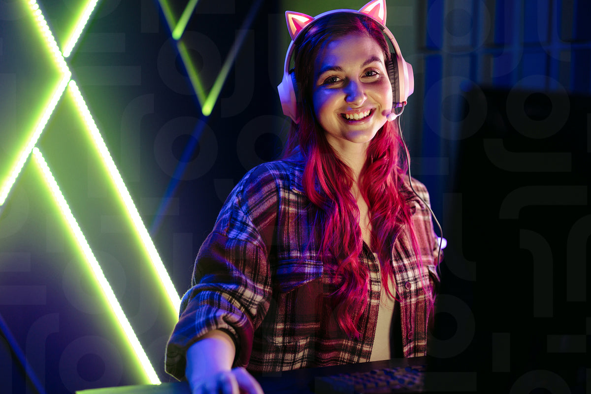 Portrait of a happy female gamer sitting in front of a gaming computer ...