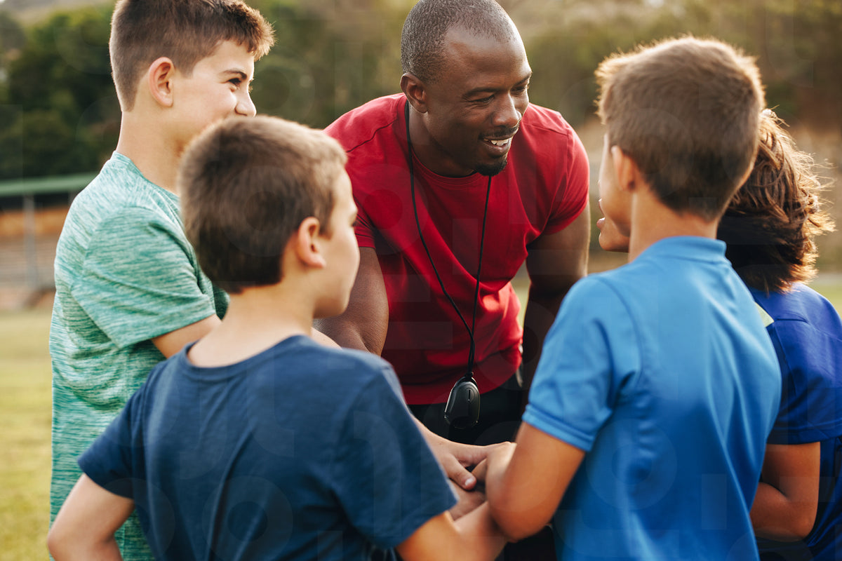Sports coach having a huddle with his school team in a field – Jacob ...
