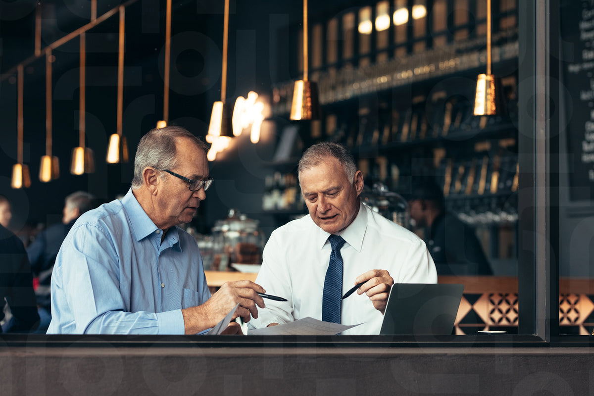 Senior men discussing a business document in cafe – Jacob Lund ...