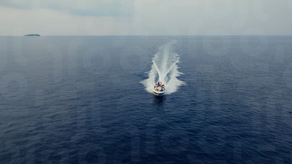 Boat speeds across the vast blue ocean leaving a foamy wake behind it ...