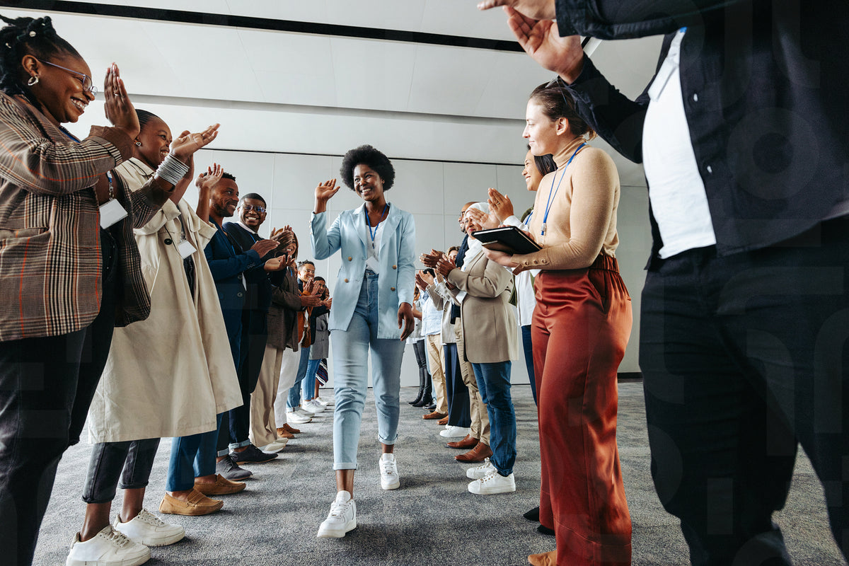 Female business leader receiving applause from colleagues in office ha ...