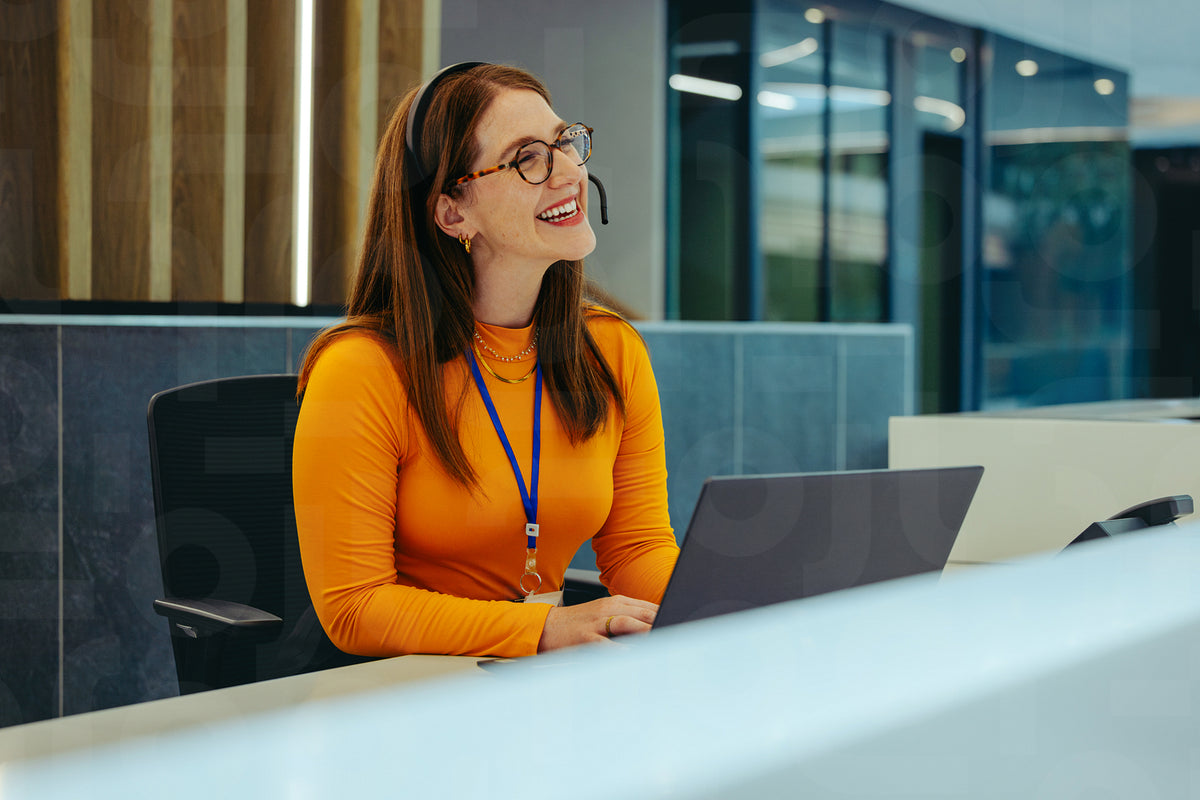 Friendly receptionist in a high-rise office building greeting clients ...