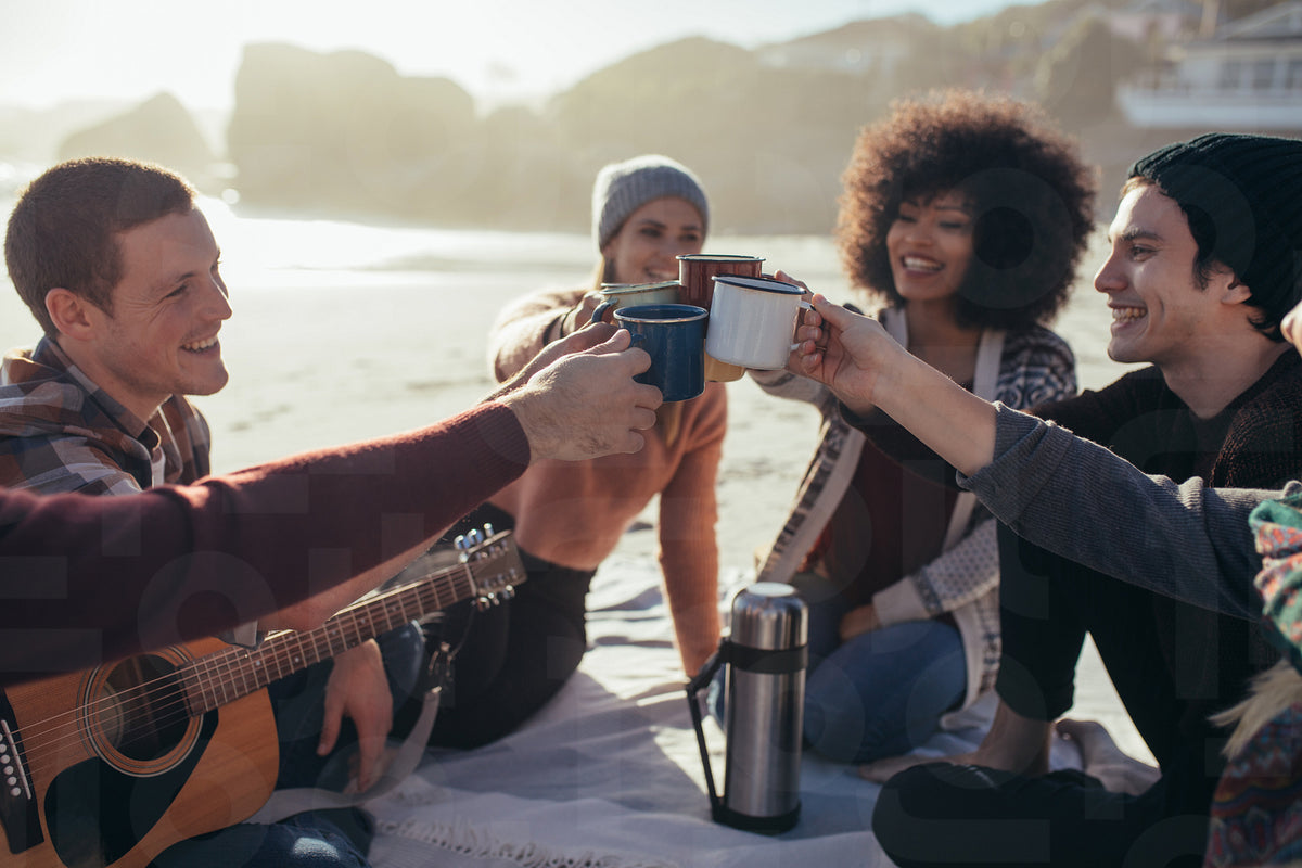 Young people toasting with coffee cups on beach – Jacob Lund ...