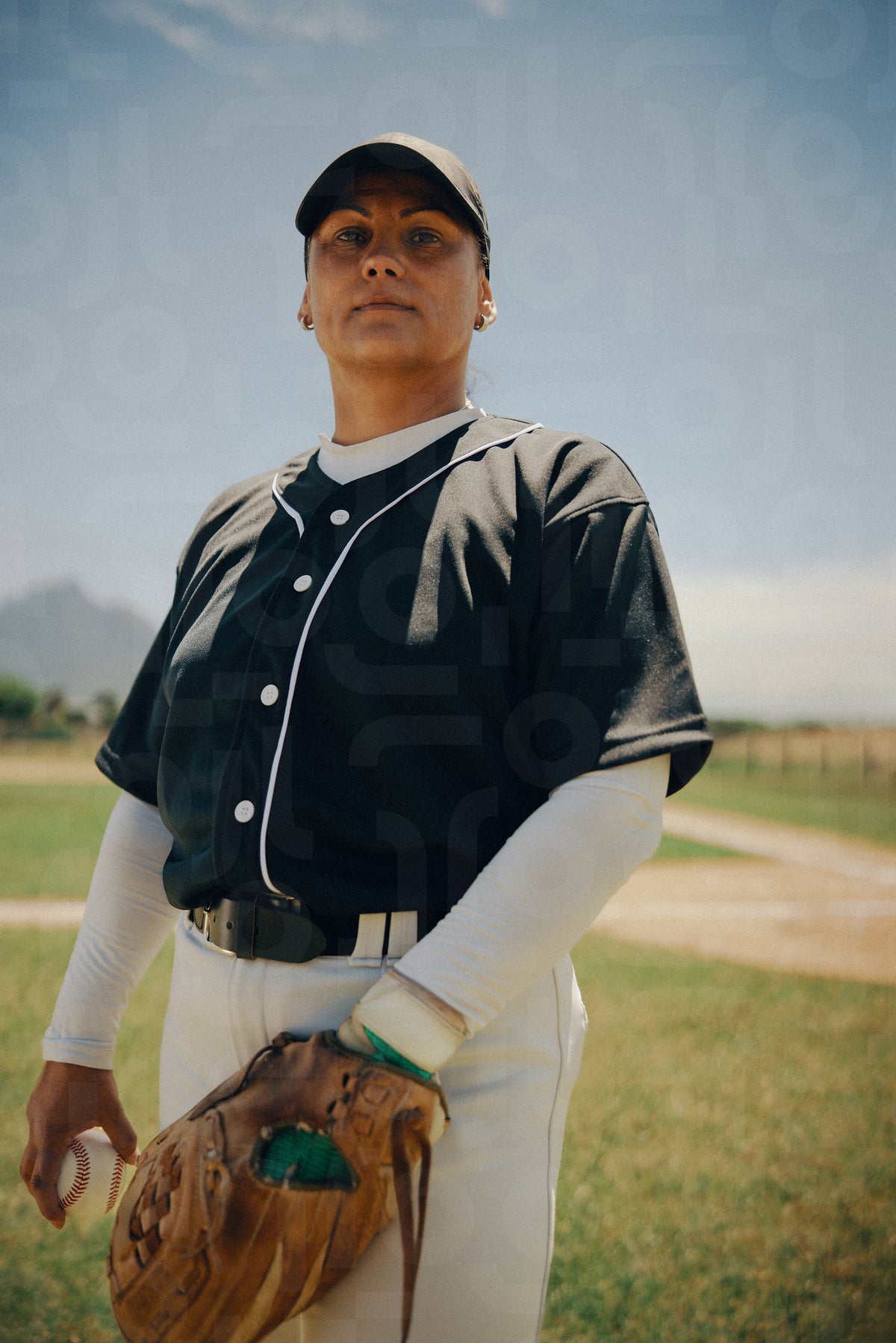 Confident female baseball pitcher standing on the field ready to throw ...