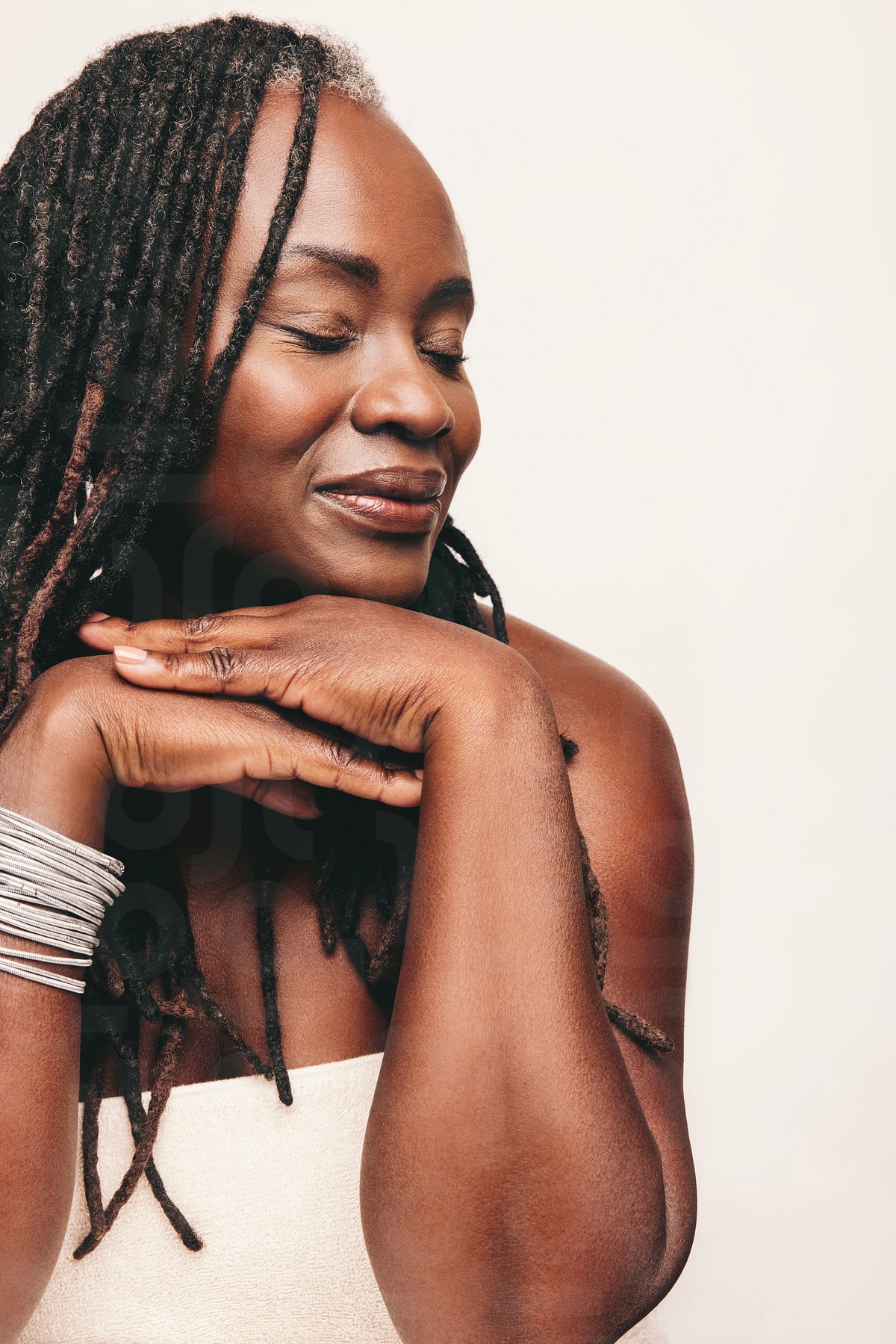 Elegant woman with dreadlocks wearing a bath towel against a studio ba ...