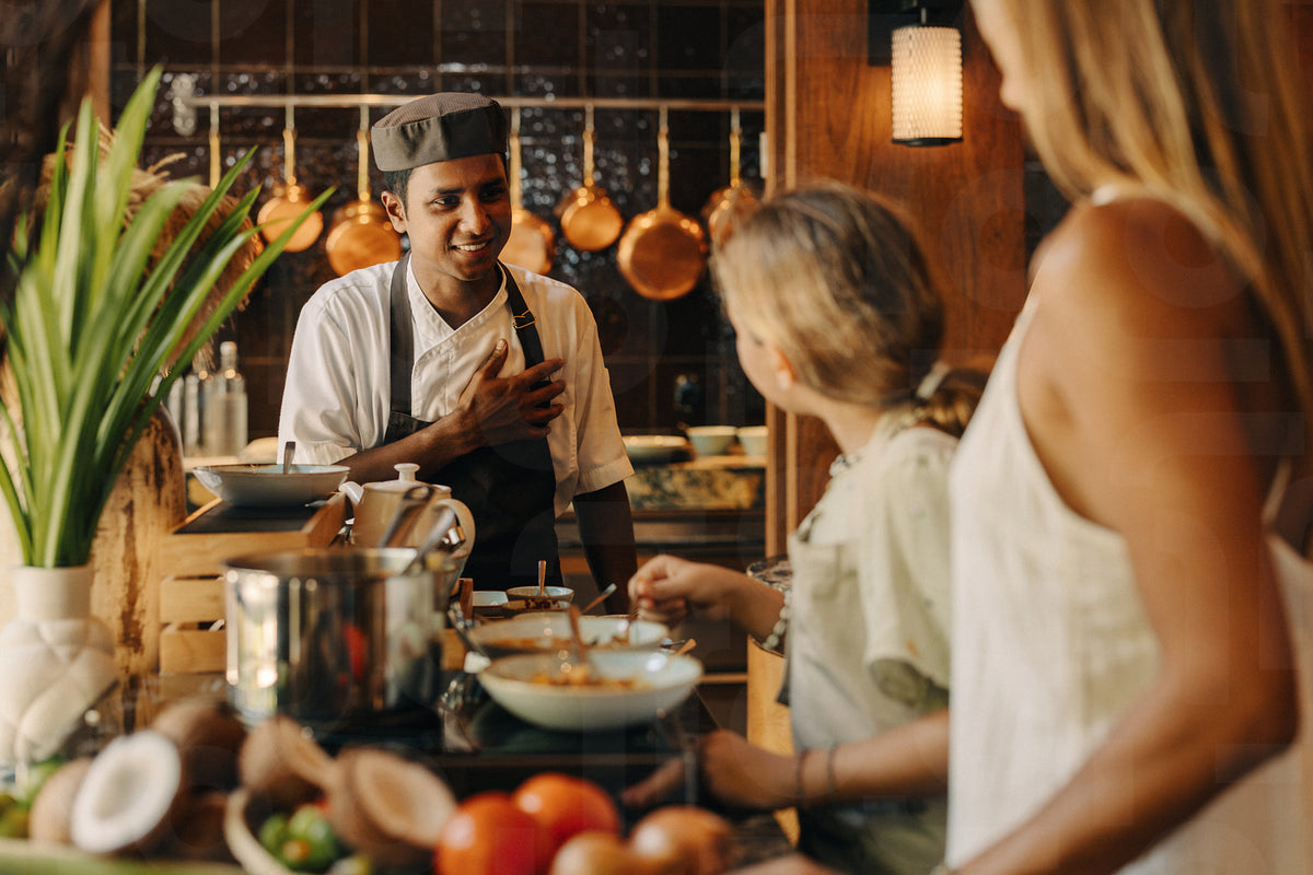 Chef interacting with customers in a warm and welcoming kitchen enviro ...