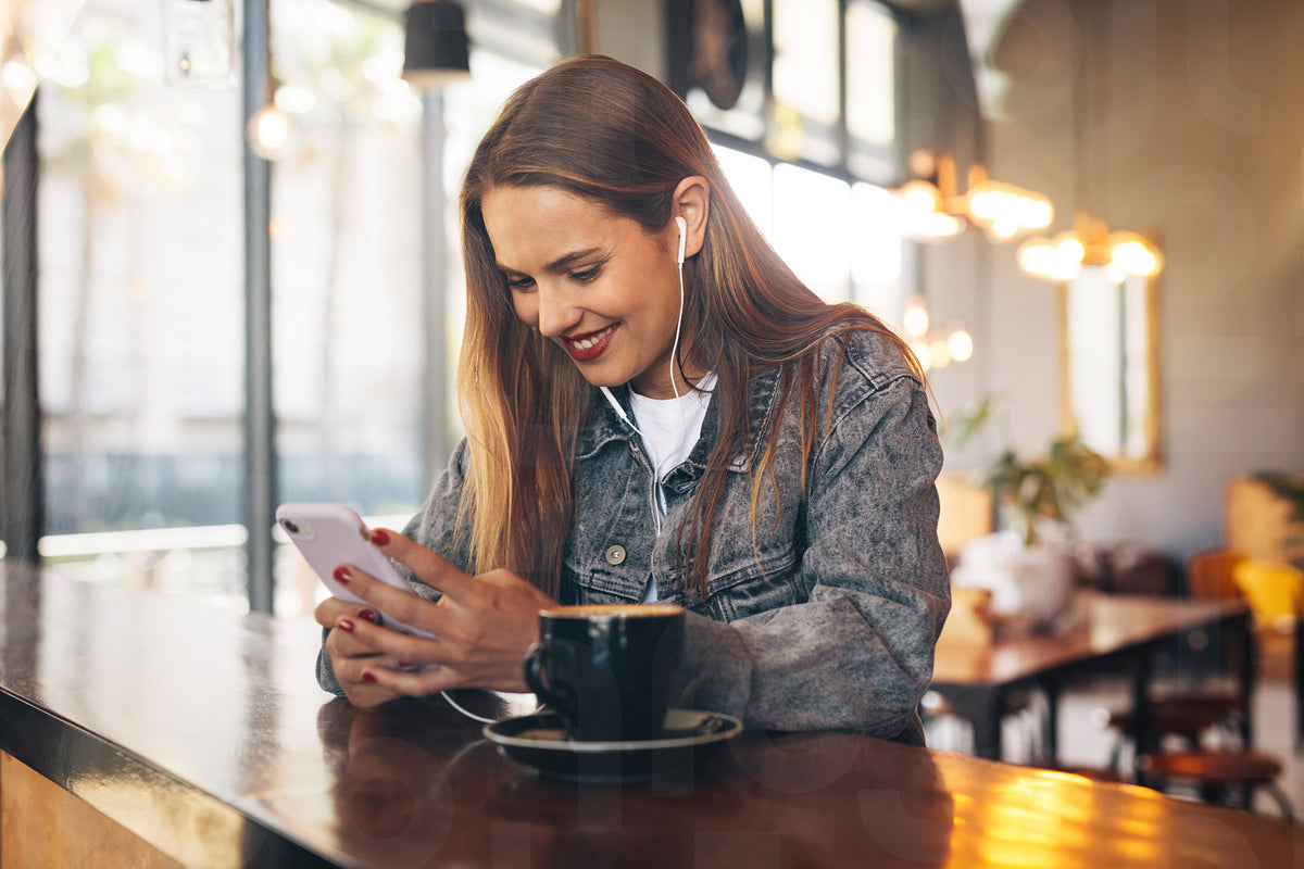 Woman in coffee shop listening to music from cell phone – Jacob Lund ...
