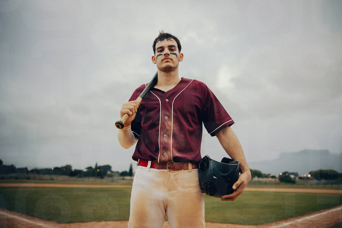 Confident baseball player standing on the field holding a bat and helm ...