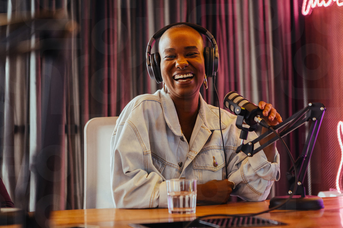Joyful female radio presenter recording in studio with professional eq ...
